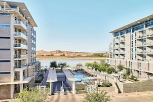 Um hotel moderno com vários andares, piscina e vista para um lago e montanhas.