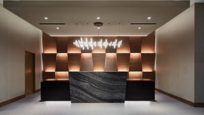 Uma área de recepção com balcão de mármore, iluminação embutida e design geométrico na parede.