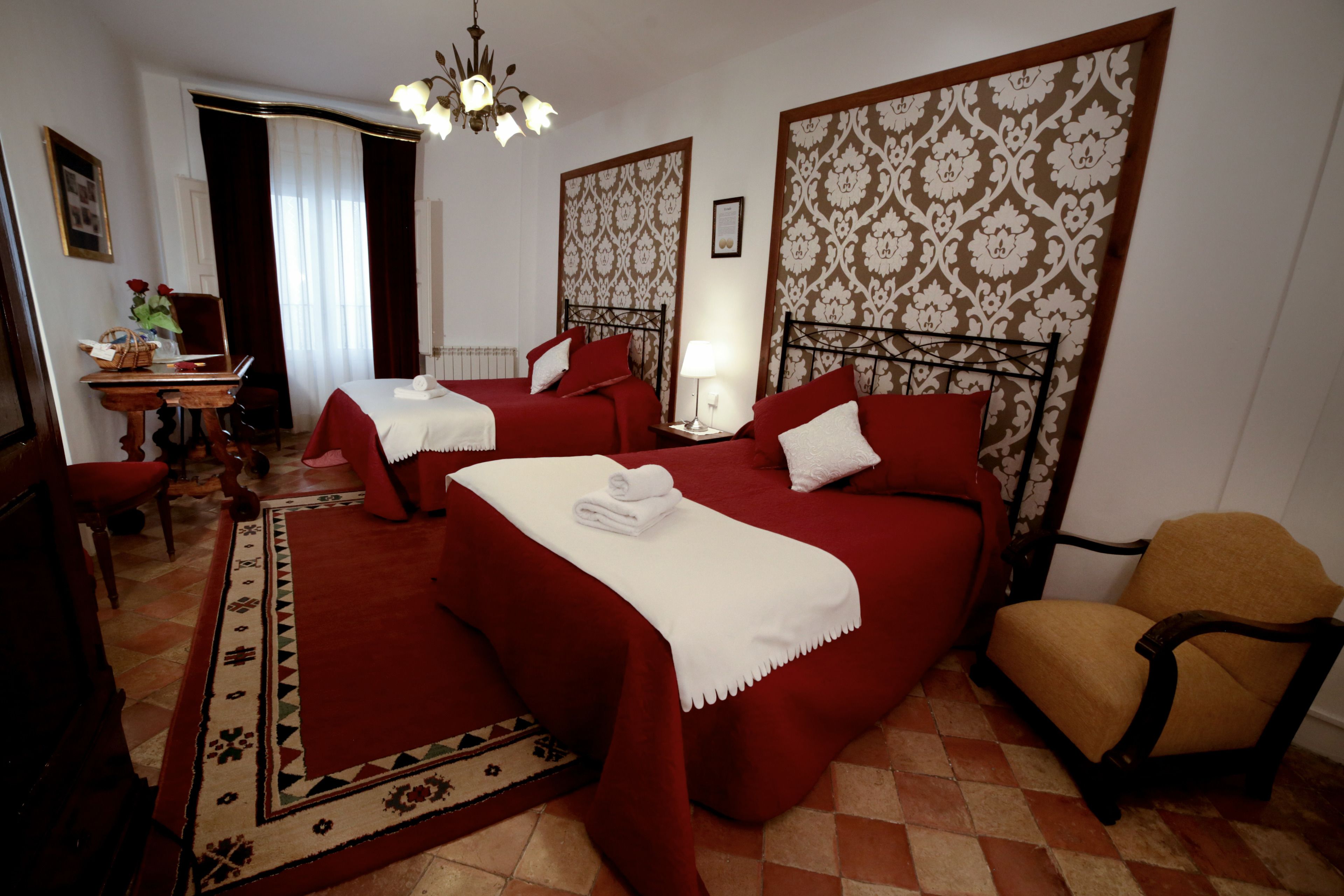 Quarto de hotel com duas camas, um espaço de estar e uma pequena mesa com uma cadeira.