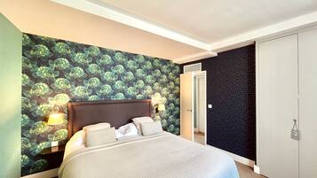 Quarto com uma cama, mesa de cabeceira, luminária na parede e uma porta.