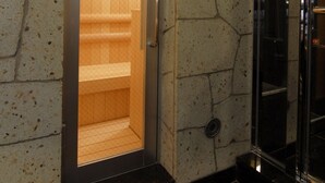 Um quarto com paredes de pedra e interior de madeira, uma porta e uma porta de elevador de vidro.