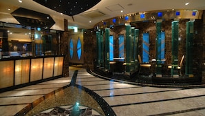 Um hall de hotel moderno com balcão de recepção, área de estar e piso de mármore curvo.