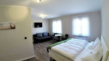 Quarto de hotel moderno com cama, sofá, escrivaninha e televisão.