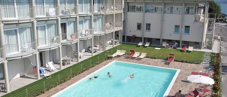 Um hotel com piscina, várias varandas e áreas de estar ao ar livre.