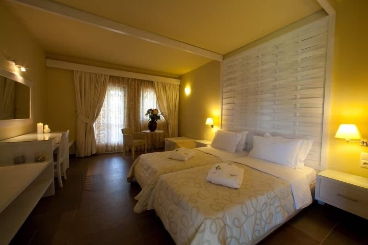 Quarto de hotel com duas camas, uma escrivaninha, uma cadeira e uma mesa pequena.