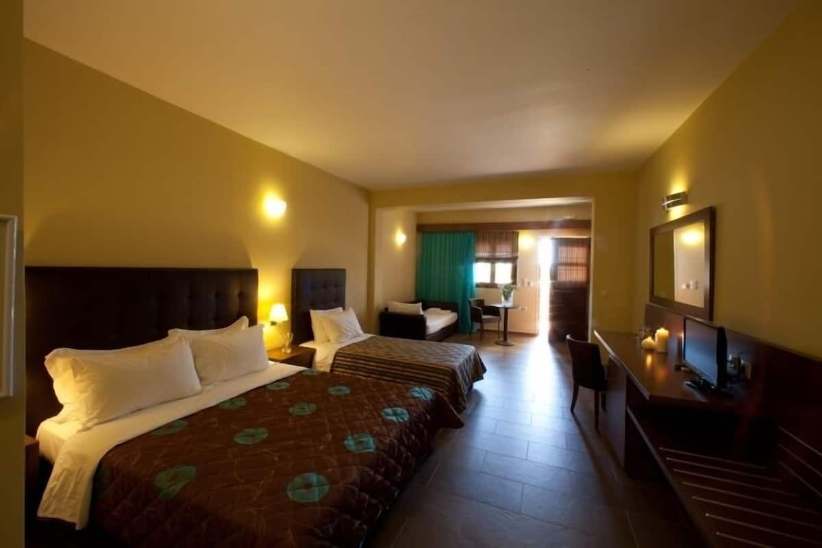Quarto de hotel com duas camas, uma escrivaninha, uma TV e uma pequena área de estar.