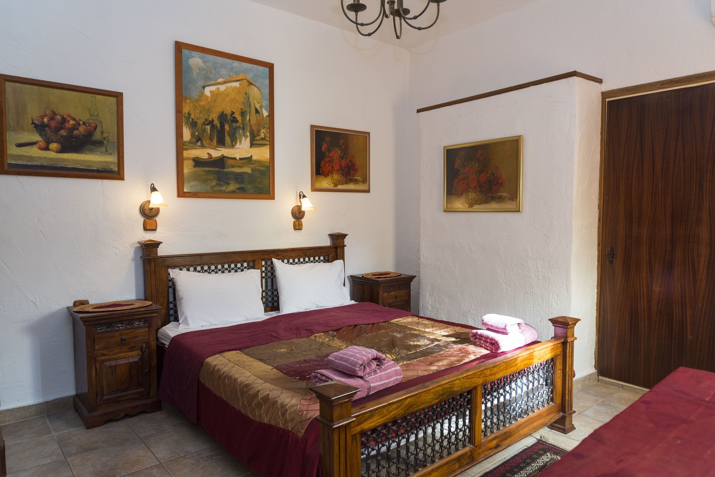 Quarto com cama de madeira, mesa de cabeceira, cômoda e uma janela grande.