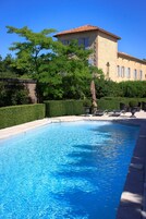 Piscina com um edifício de pedra ao fundo.