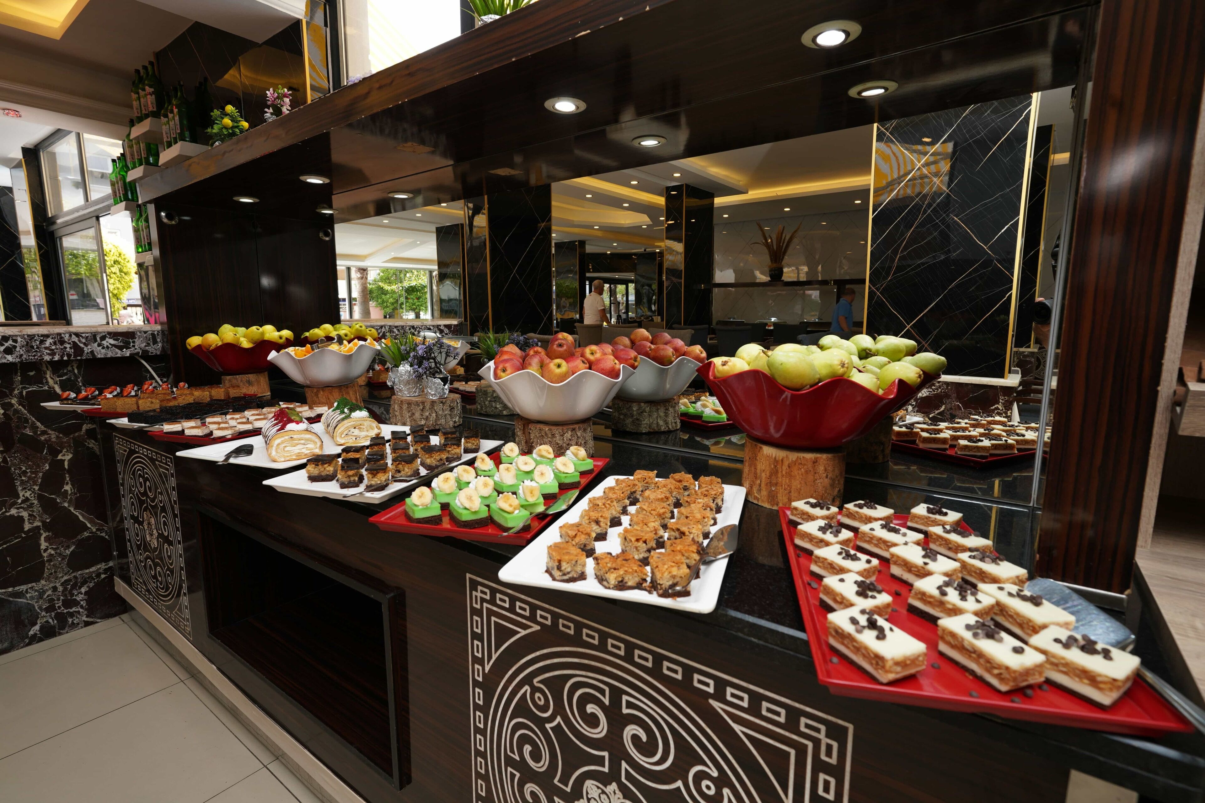 Buffet com diversas opções de comida, incluindo frutas, sobremesas e doces.