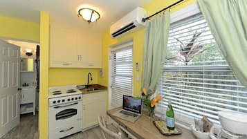 Cozinha com fogão, pia e um laptop no balcão.