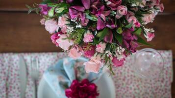 Uma mesa posta com arranjo de flores, um prato e um copo.