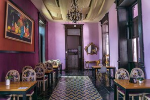 Uma sala de jantar com paredes roxas, piso estampado e cadeiras florais.