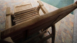 Pequena piscina ao ar livre com um banco de madeira em primeiro plano.
