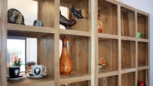 Uma estante de madeira com diversos objetos decorativos, incluindo um vaso, xícaras e figuras.