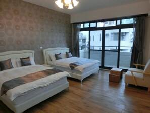 Quarto de hotel com duas camas, uma janela grande com vista para edifícios e piso de madeira.