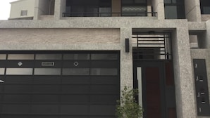 Um edifício de vários andares com arquitetura moderna, destacando uma porta de garagem e um pequeno vaso com planta em frente.