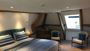 Quarto com cama grande, uma cadeira, escrivaninha e janela.