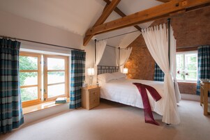 Quarto com cama de dossel, mesa de cabeceira, janela com cortinas e parede de pedra.