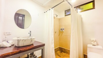 Um banheiro com pia de mármore, chuveiro com porta de vidro e vaso sanitário.