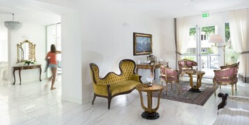 Um hall amplo com um sofá amarelo, uma mesa redonda e um candelabro.