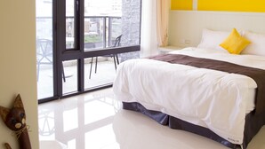 Quarto de hotel com uma cama grande, um candelabro, vista através de uma porta de correr de vidro e uma escultura de gato.