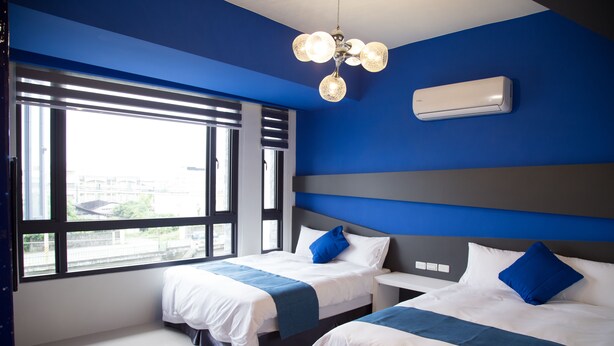 Quarto de hotel com duas camas, uma janela grande e um aparelho de ar condicionado na parede.