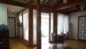 Um quarto japonês tradicional com vigas de madeira, tatames e portas deslizantes, com vista para o exterior.