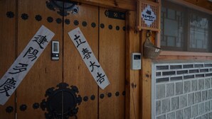 Uma porta de madeira com caracteres japoneses e uma pequena placa em cima.
