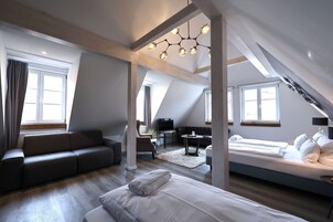 Um quarto moderno no estilo loft, com uma cama grande, um sofá e uma televisão.
