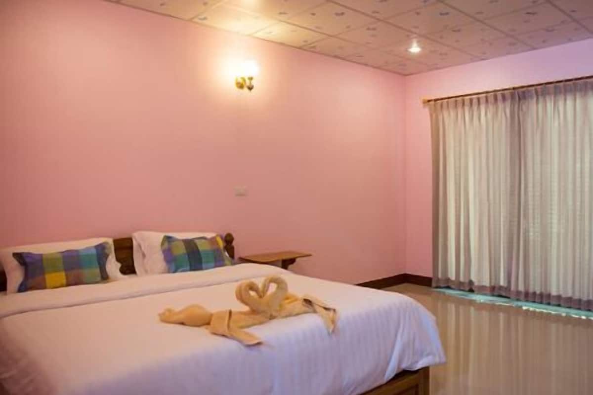 Quarto com cama, almofadas, mesa de cabeceira e janela com cortinas.