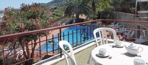Uma varanda com piscina, cadeiras brancas e mesa posta para chá.