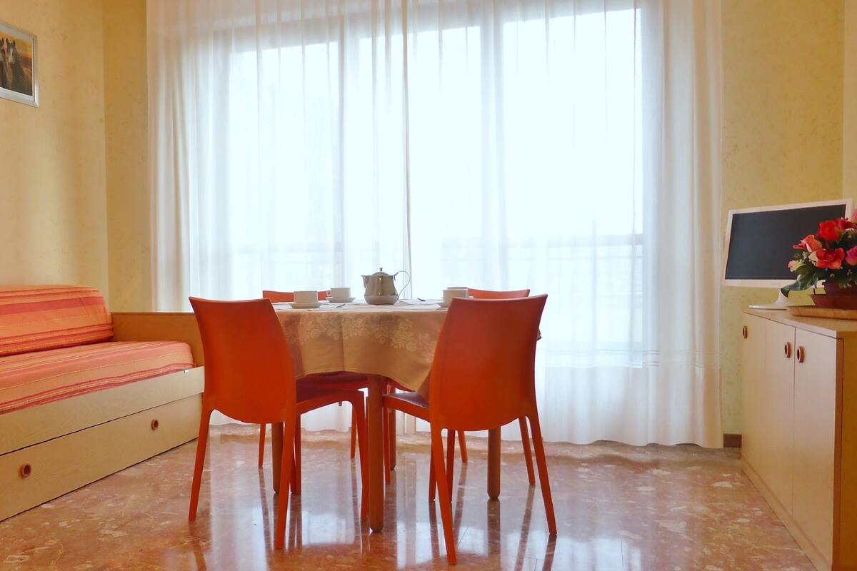 Quarto com sofá, mesa de jantar, cadeiras e um armário.