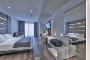 Quarto de hotel moderno com uma cama grande, uma escrivaninha, uma cadeira e uma televisão.