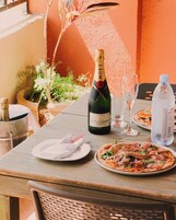 Uma mesa posta para refeição com uma garrafa de champanhe Moët, duas taças, uma garrafa de água e pratos de comida.