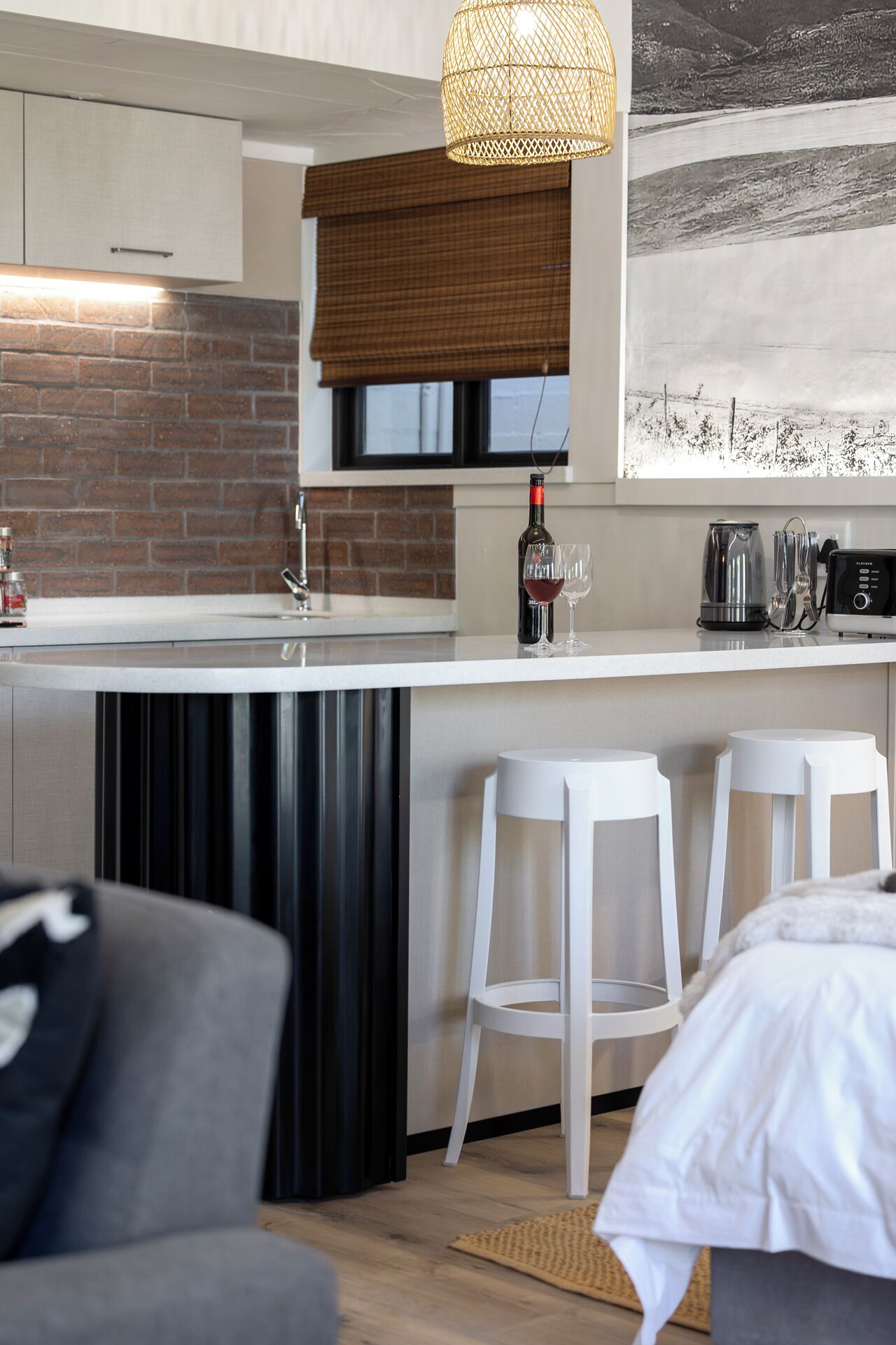 Uma cozinha moderna com uma ilha central, banquetas brancas e um espaço de refeições com sofá.
