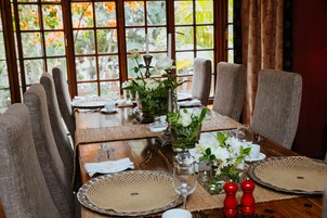 Mesa de jantar posta com jogos americanos, velas e arranjos florais.