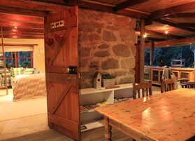 Interior rústico de cabana com parede de pedra, móveis de madeira e um espaço de estar acolhedor.