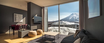 Sala de estar moderna com uma janela grande que oferece vista para uma montanha coberta de neve.