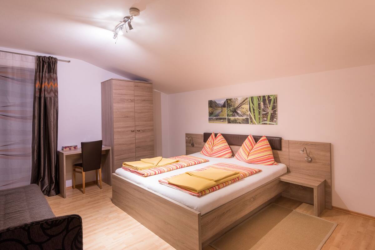 Quarto com cama, escrivaninha, cadeira, guarda-roupa e um quadro na parede.
