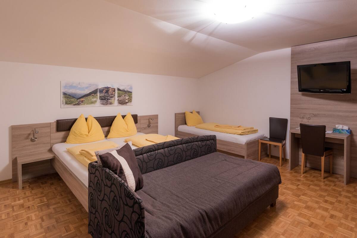 Quarto de hotel moderno com uma cama grande, uma escrivaninha e uma televisão.