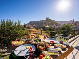 Mesa posta com diversos pratos e vista para uma cidade histórica com um castelo ao fundo.