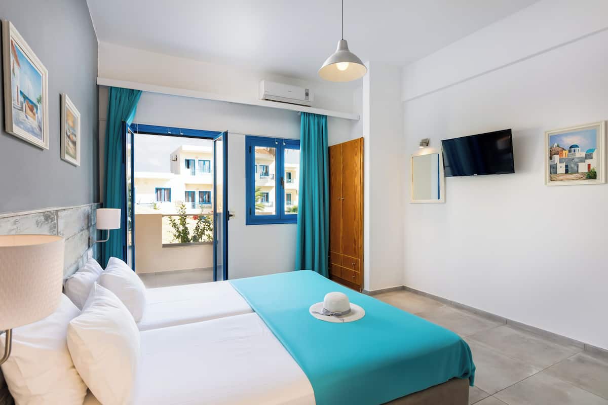 Quarto de hotel com cama, televisão e vista para edifícios.