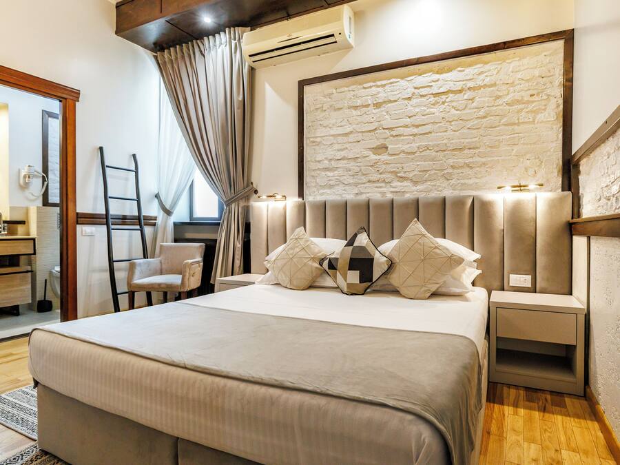 Quarto moderno com uma cama grande, cabeceira com parede texturizada, mesa de cabeceira e uma cadeira.
