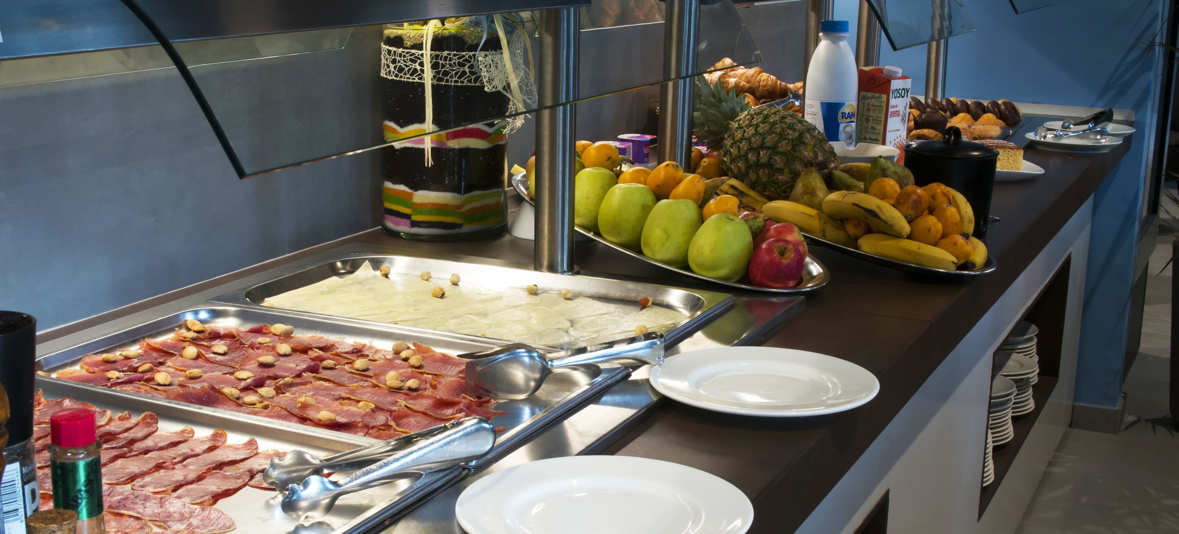 Buffet com diversas opções de comida, incluindo carnes, frutas e doces.