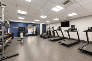 Uma academia com esteiras, elípticos e equipamentos de musculação.