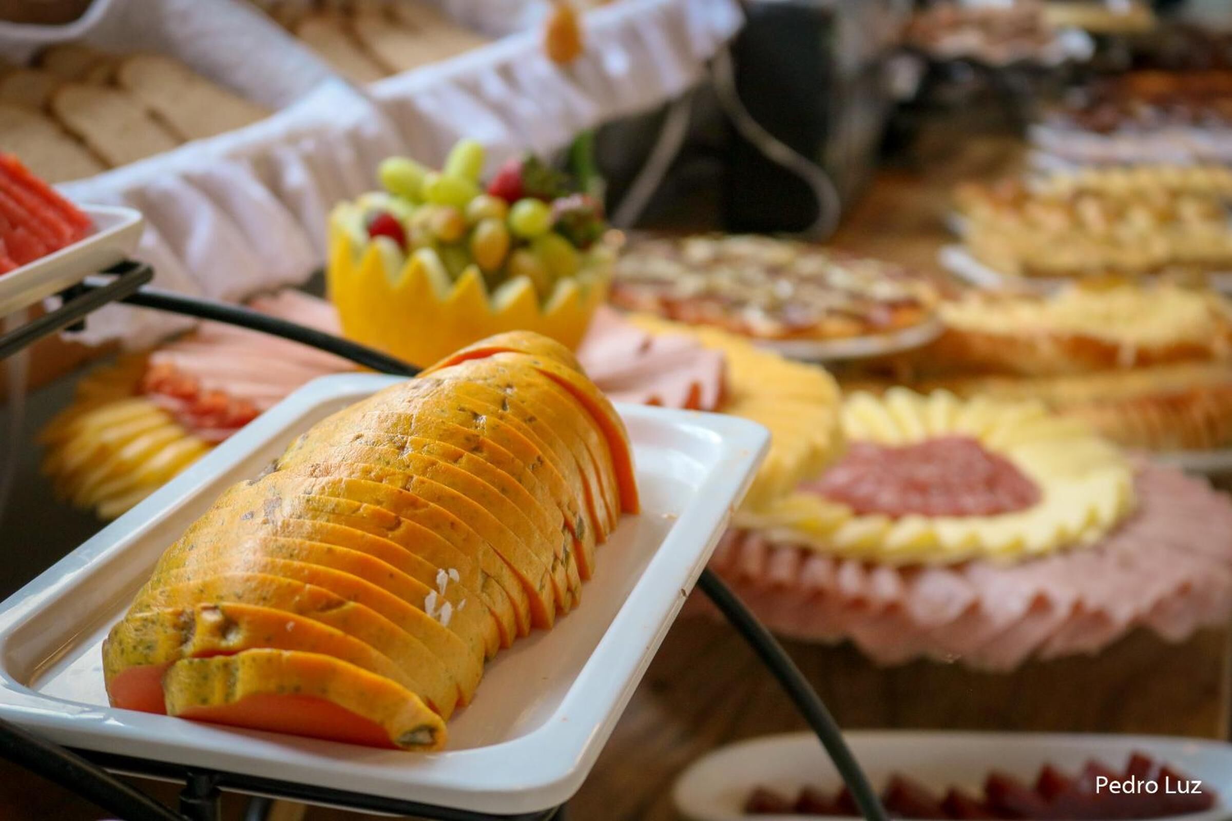 Buffet com diversos pratos, incluindo uma salada de laranja fatiada, salada de frutas e outros alimentos.