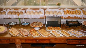 Vitrine de padaria com diversos pães, doces e sobremesas.