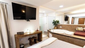 Uma casa de banho moderna com um espelho grande, uma banheira, uma toucador com lavatório e uma televisão na parede.
