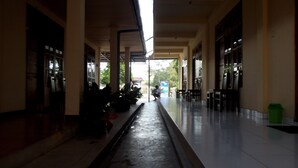 Um corredor com piso de azulejos, bancos e plantas em vasos.