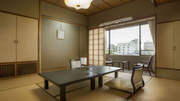Um quarto japonês tradicional com tatames, uma mesa baixa e portas deslizantes.